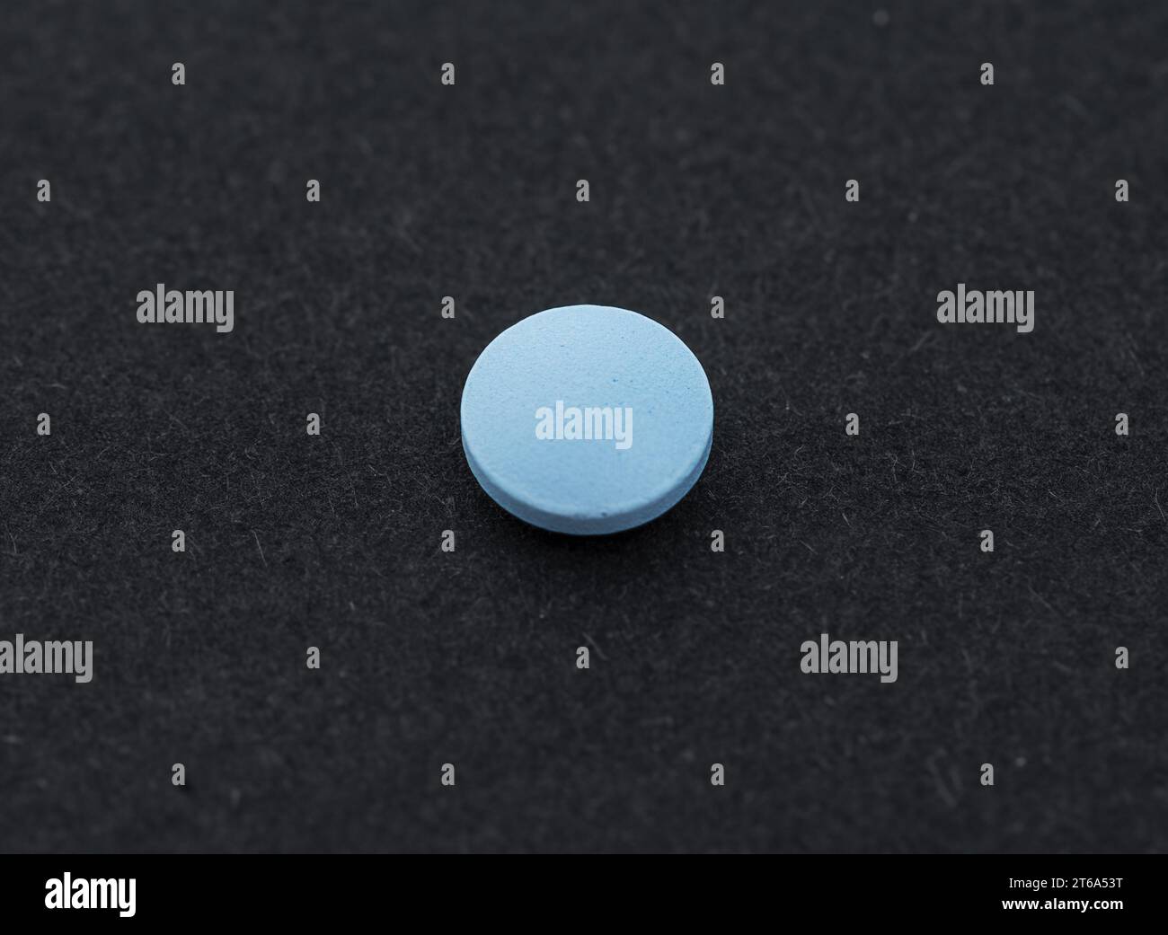 Single one blue pill, tablet or capsule on black background. Top view ...