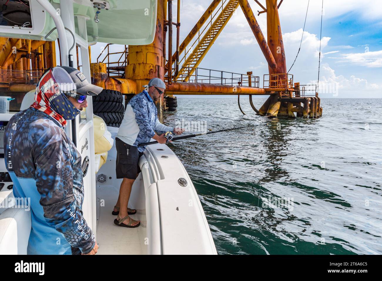 Fishermen fishing at the base of an offshore petroleum drilling rig in ...