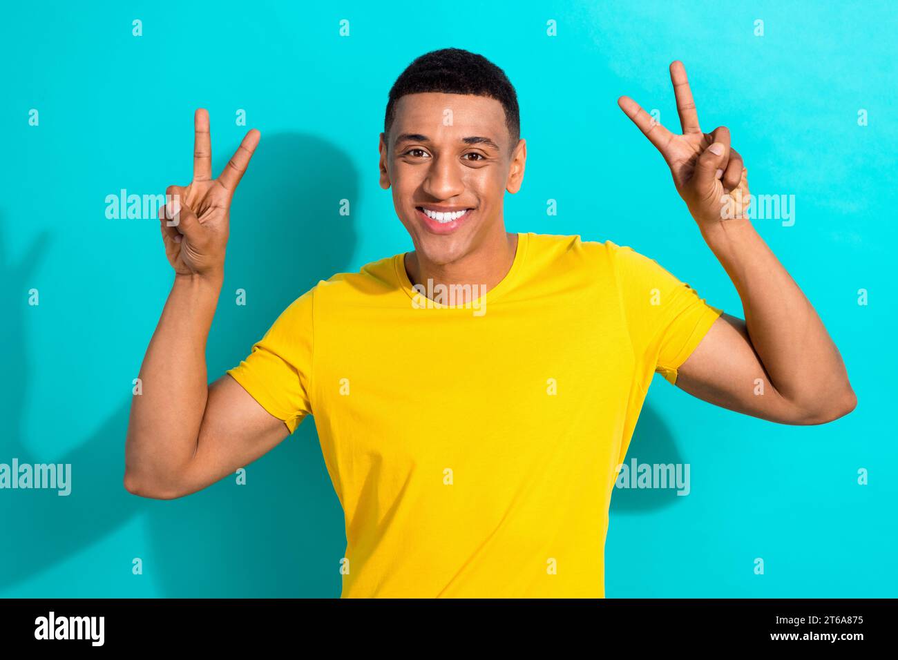 Photo of funny excited guy wear yellow t-shirt showing two v-signs ...