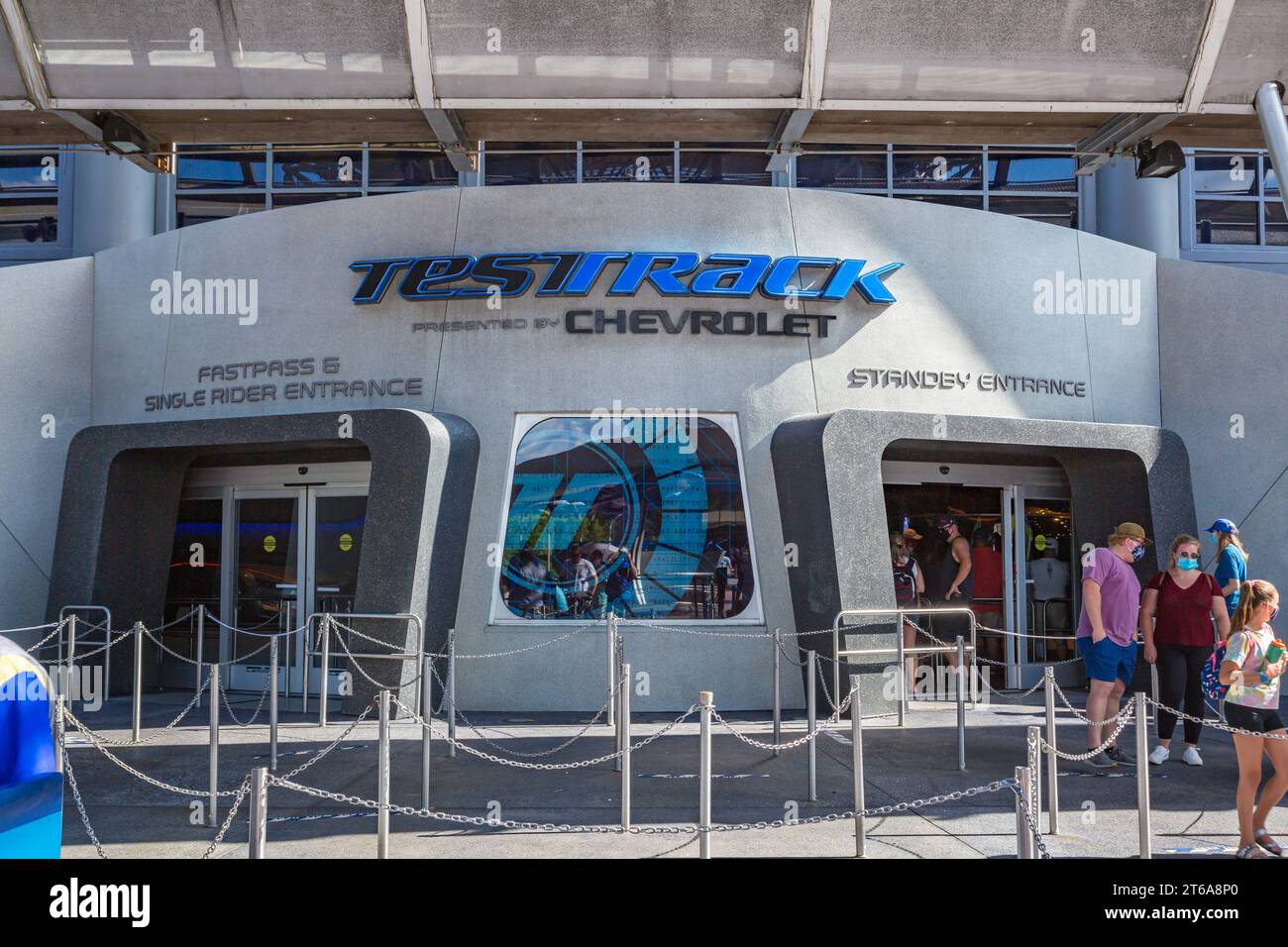 Masked park guests near the doors at the entrance to the Test Track ...