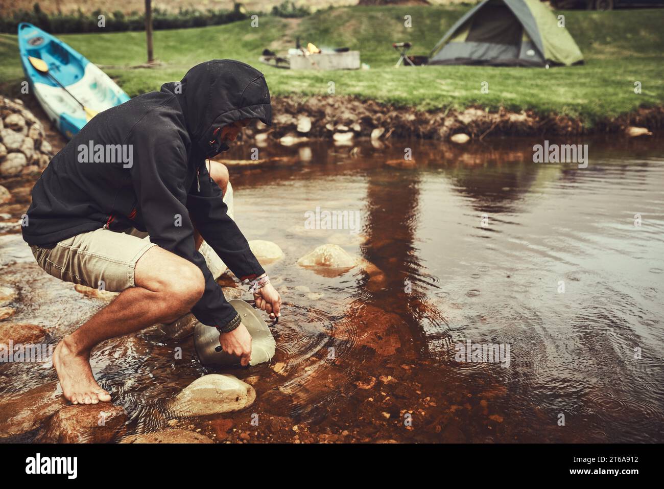 Nature has everything you need. a young man filling water from a lake ...