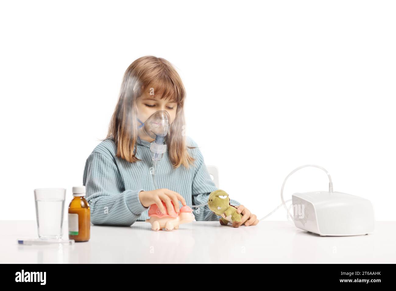 Little girl playing with toys while using a nebulizer with vapor mist ...