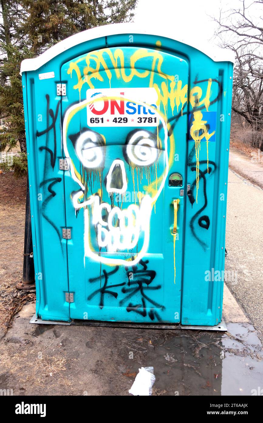 Day of the dead graffiti skull on aqua blue outdoor porta-potty toilet ...