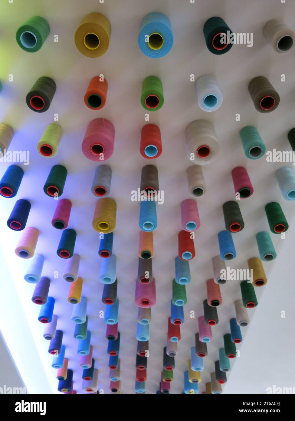 A display in lines of spools of coloured threads on the ceiling at ...