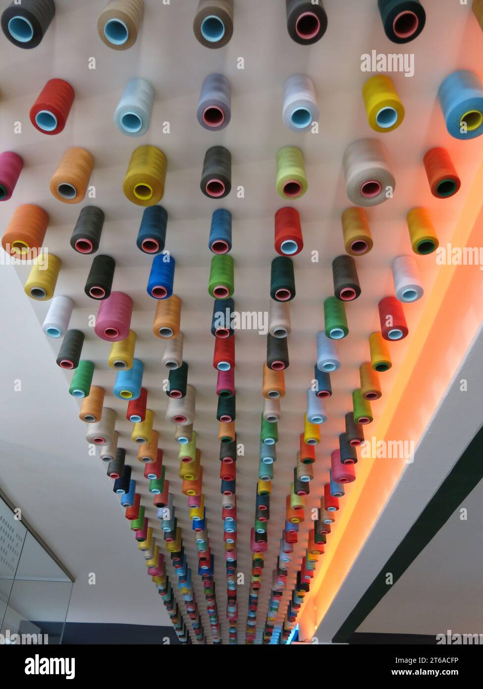 A display in lines of spools of coloured threads on the ceiling at ...