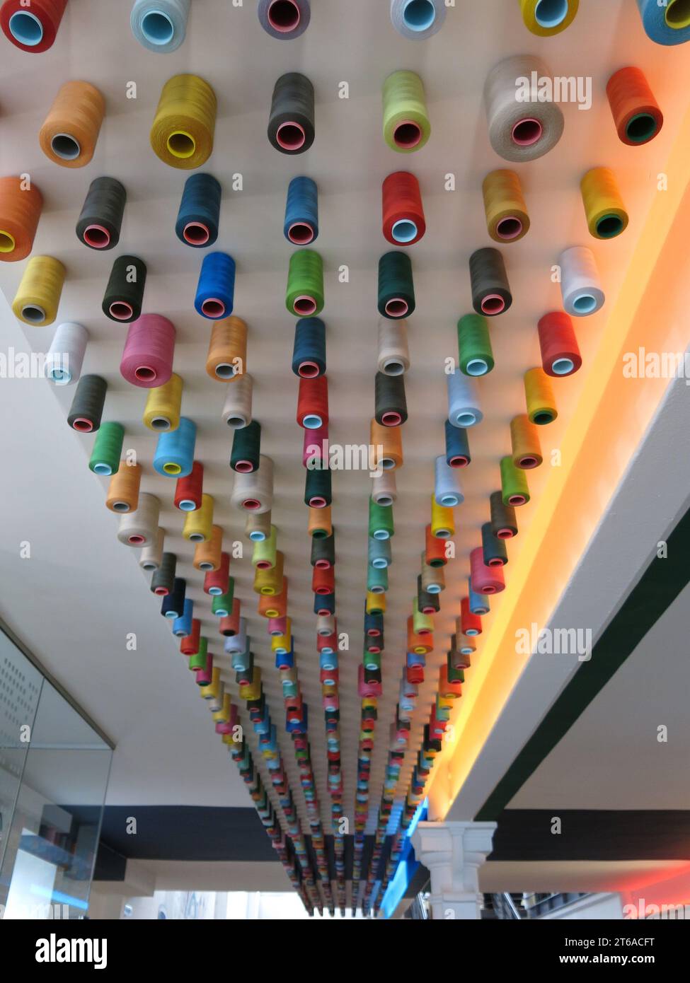 A display in lines of spools of coloured threads on the ceiling at ...