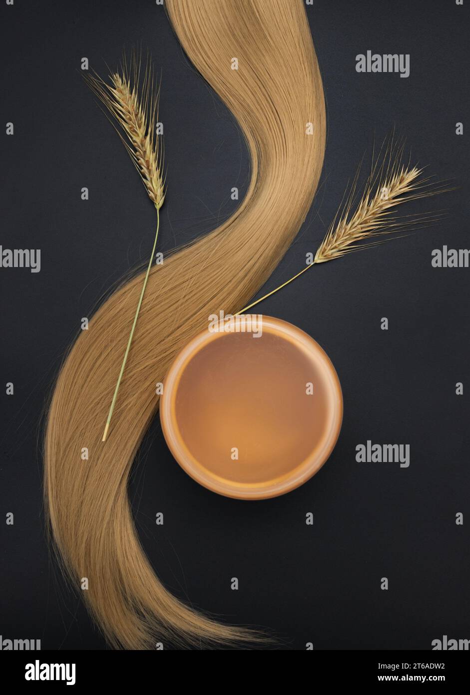 Blond long hair with cream jar and sprigs of ripe wheat. Healthy hair ...