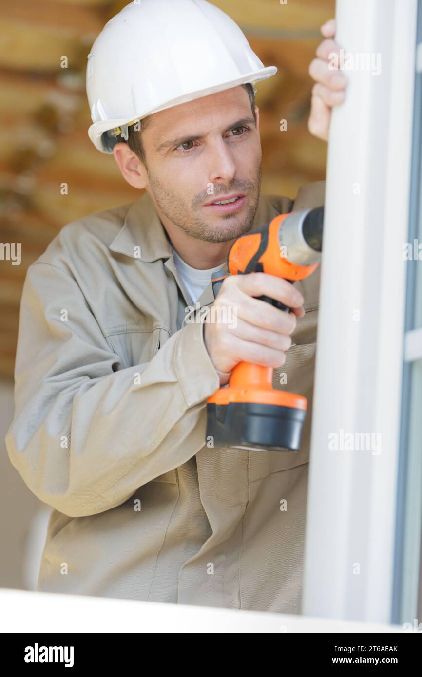 builder using cordless drill to install windows Stock Photo - Alamy