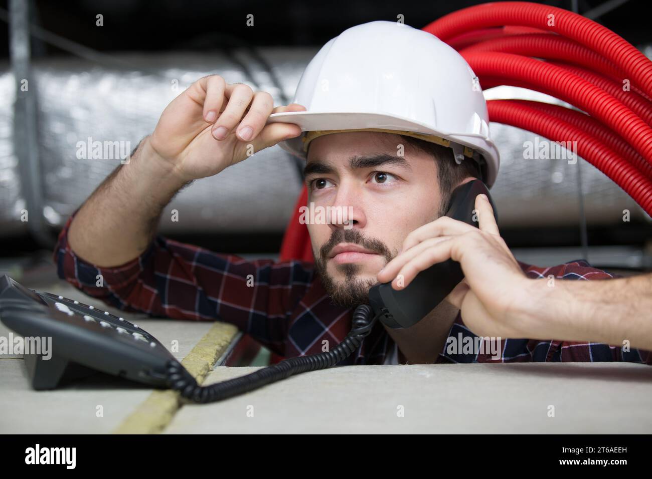 builder on cell phone crouching on elevated scaffolding near ceiling ...