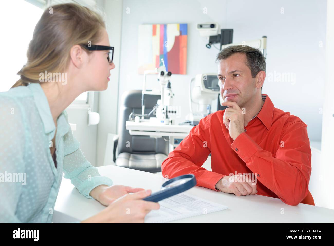 patient holding magnifying glass to read text during ophthalmologist ...