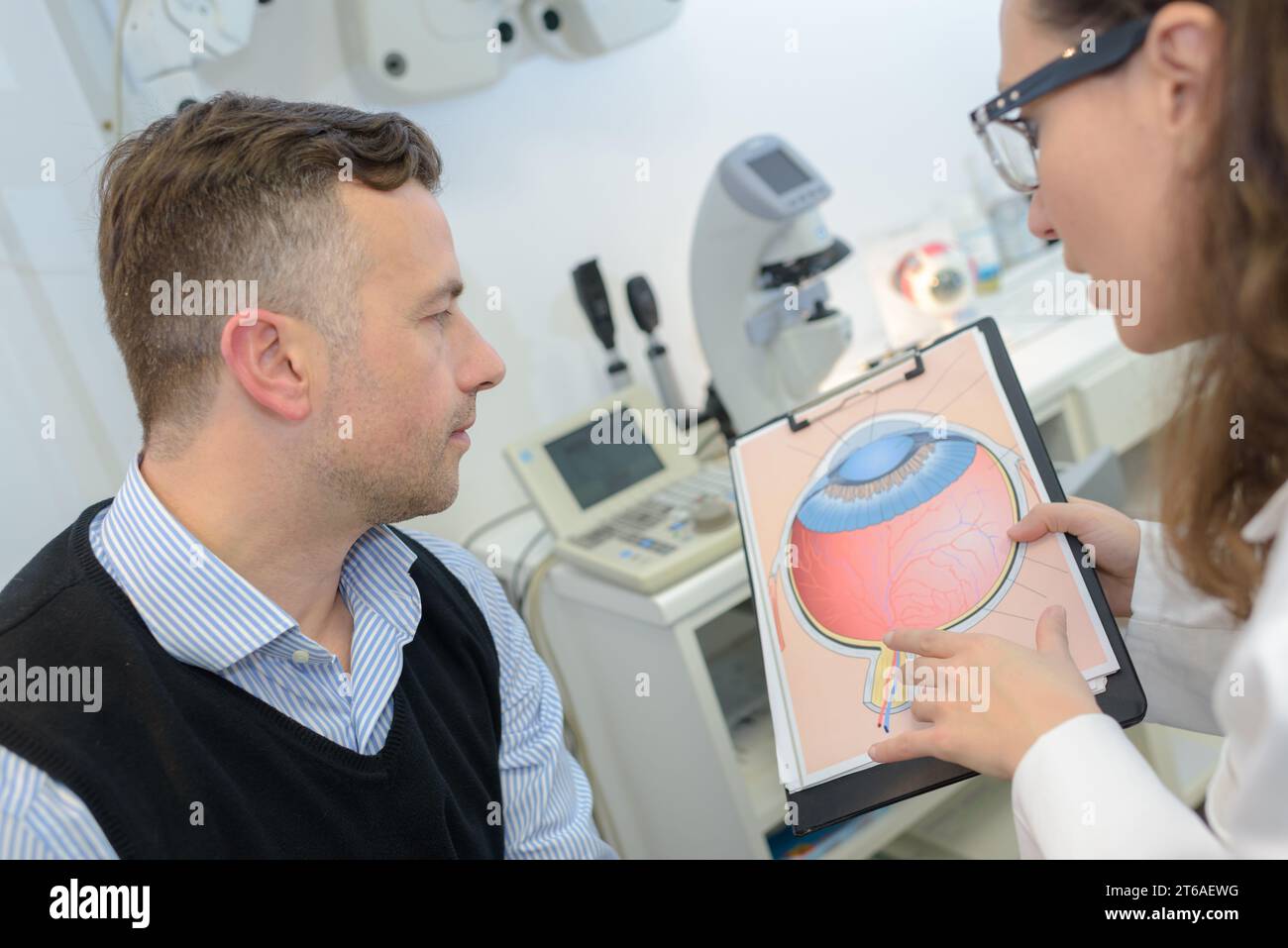 friendly female ophthalmologist explaining pathology to male patient ...