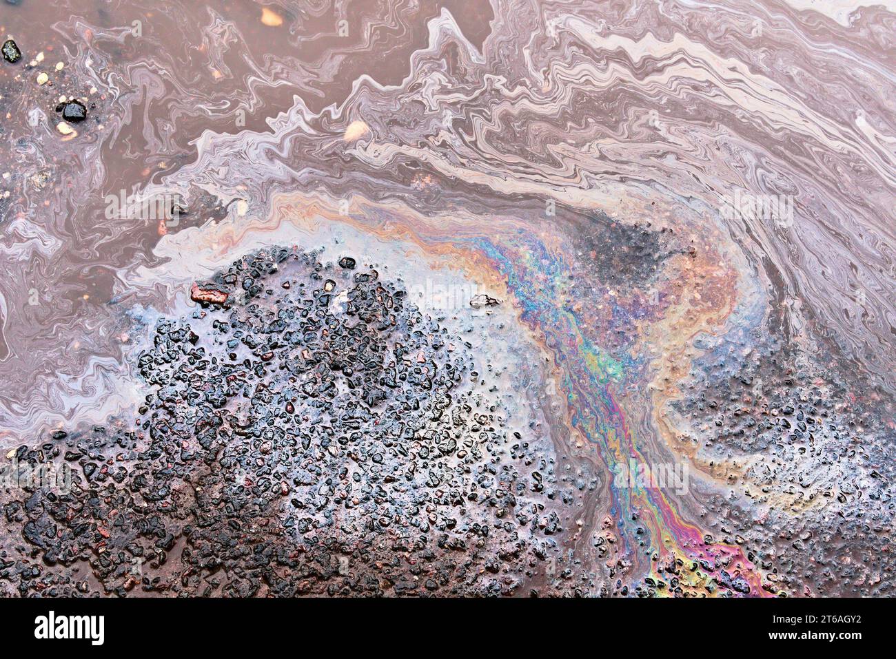 Rainbow-colored oil floating on water after rain on asphalt. Gasoline ...