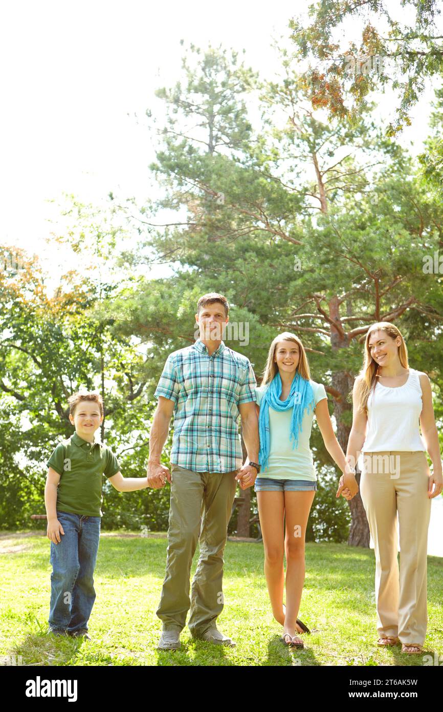 Taking a stroll together. A happy young family walking through the park ...