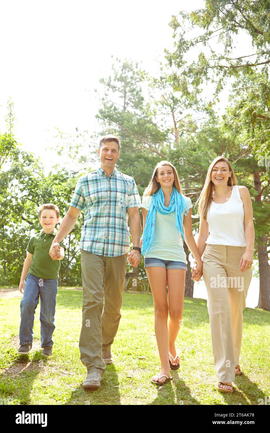 Taking a walk together. A happy young family walking through the park ...