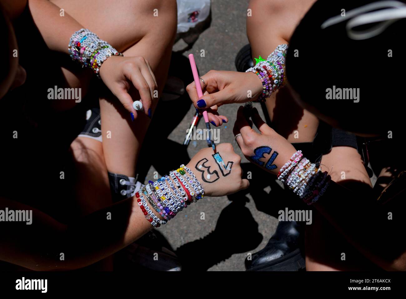 Fans of Taylor Swift paint their hands with the number 13 as they wait ...