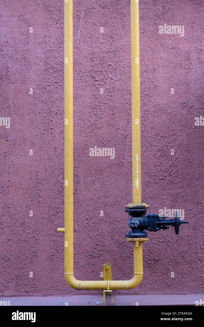 Urban still life with a yellow U-shape gas pipe and a black faucet ...