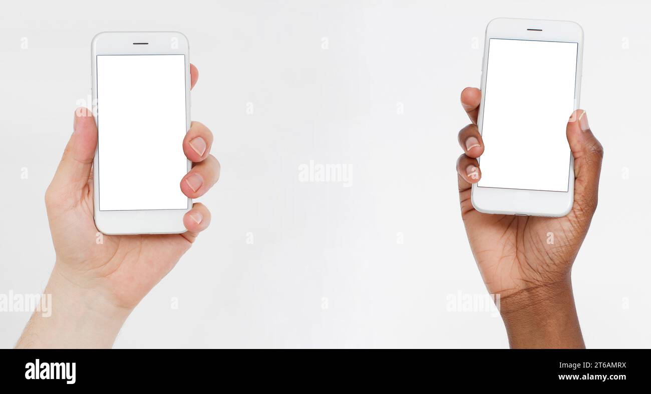 caucasian and black hands hold cell phones. Blank screen smartphone ...
