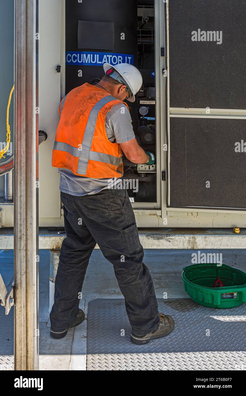 A worker working in the compressor panel of a CO2 cold-storage ...