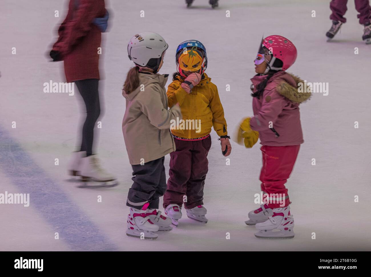 Happy children in carnival masks stand on ice rink at sports complex ...