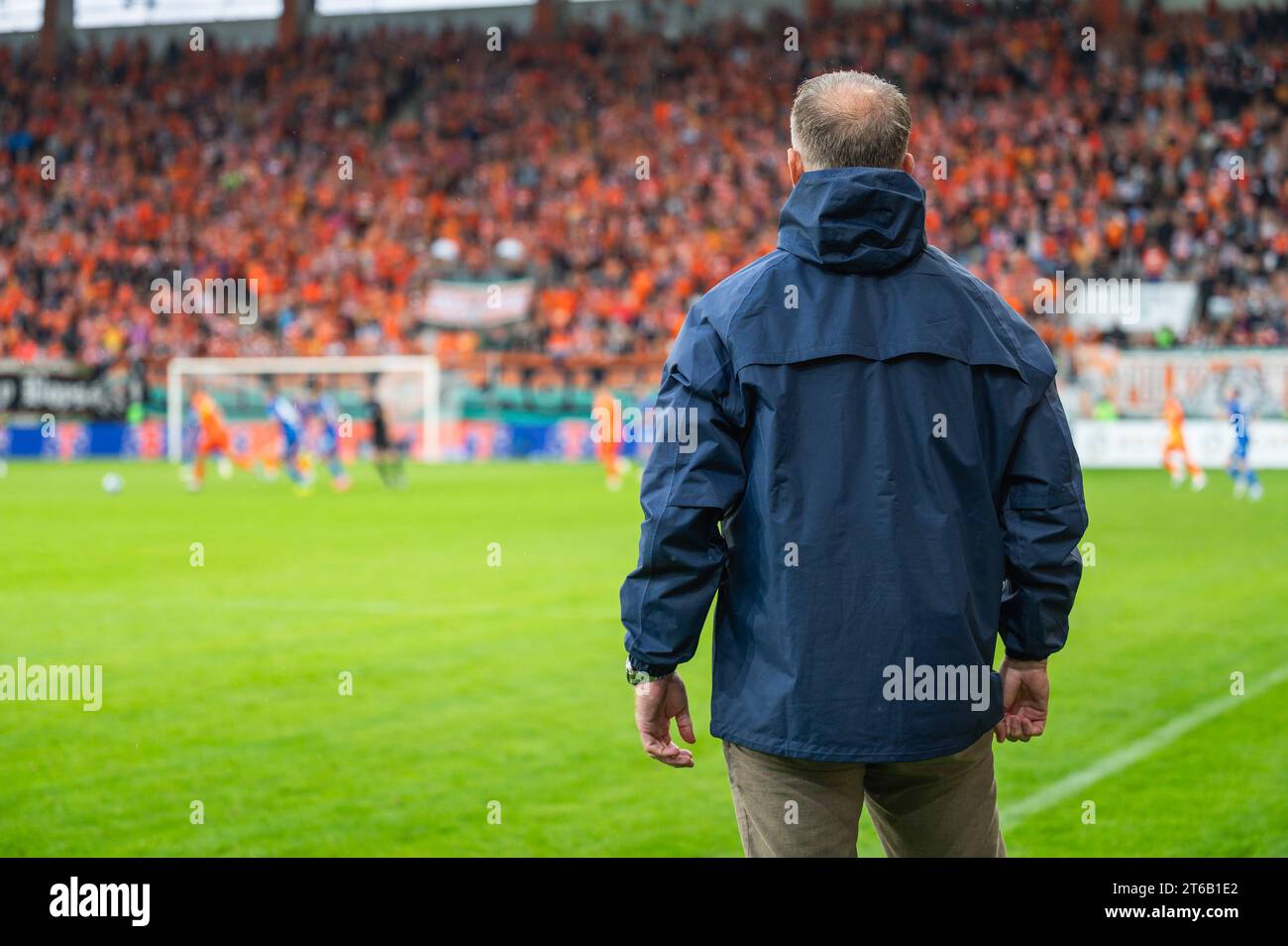 Head coach's back and soccer match at the stadium in the background ...