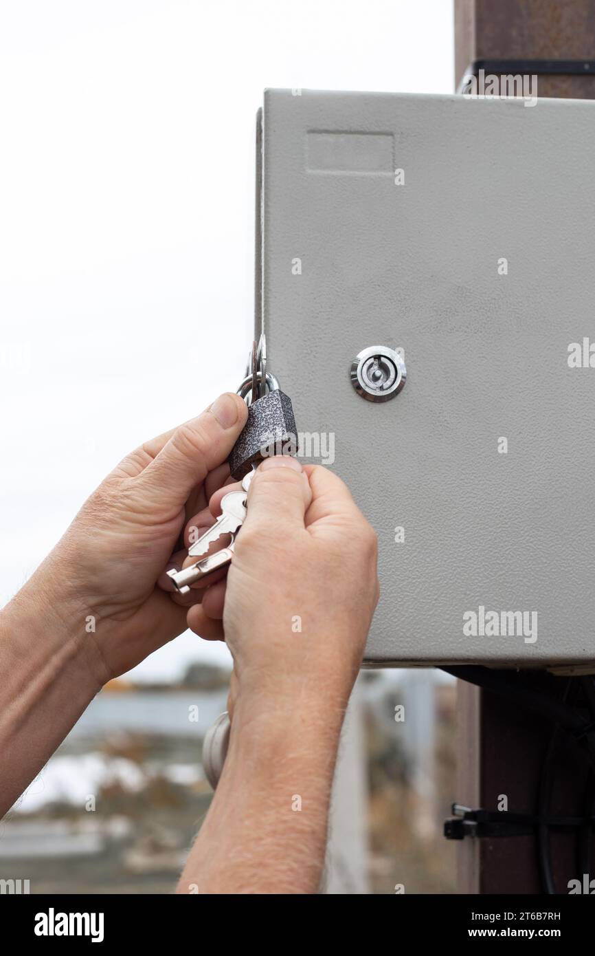An electrician locks an electrical panel with automatic switches ...