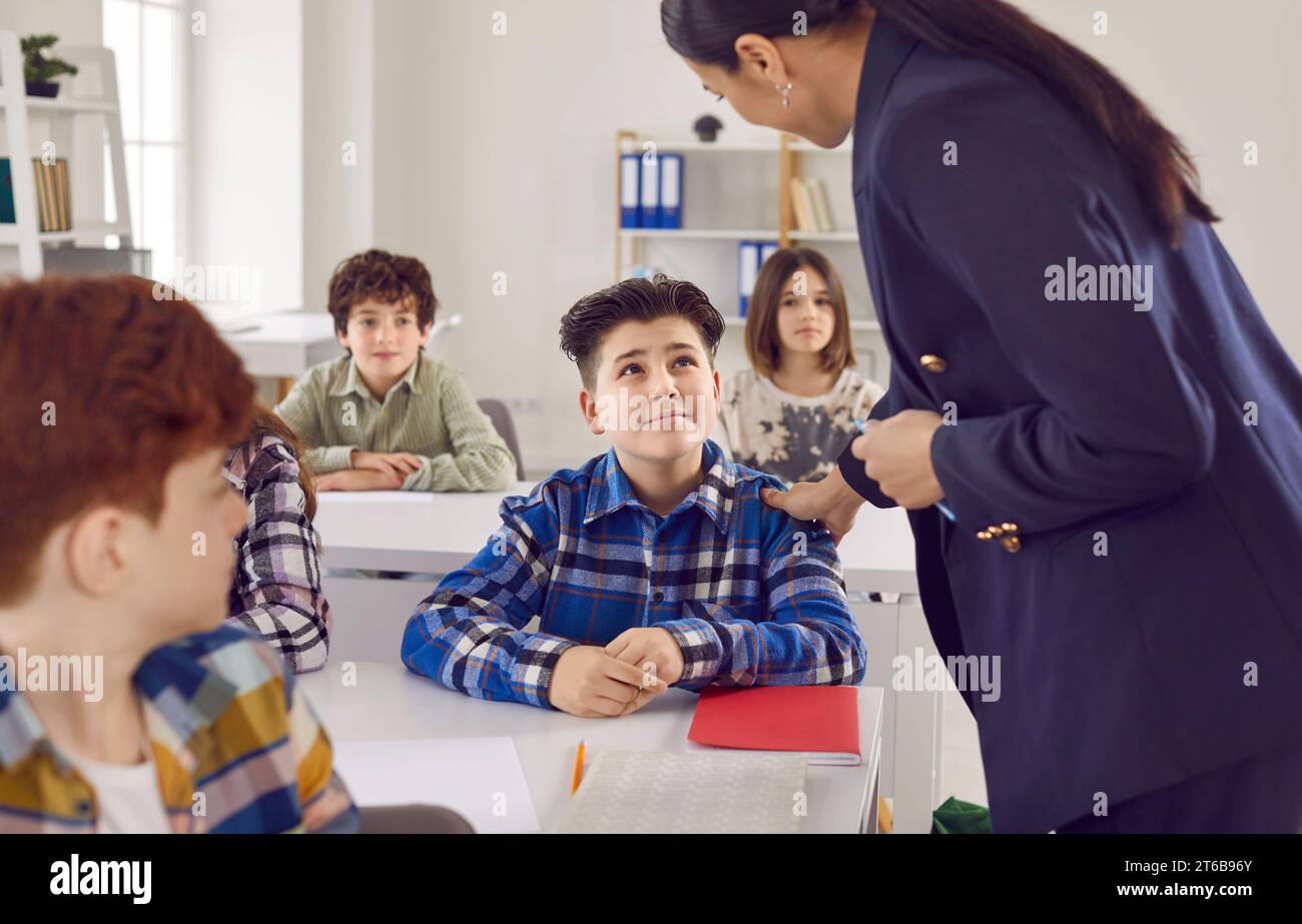 Woman teacher in junior high school helping a boy during a lesson in ...