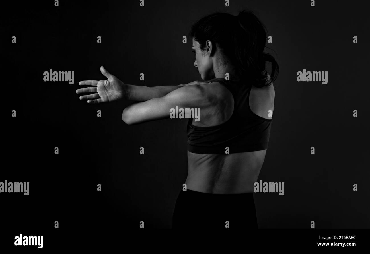 Sporty muscular woman doing stretching workout of the shoulders, blades ...