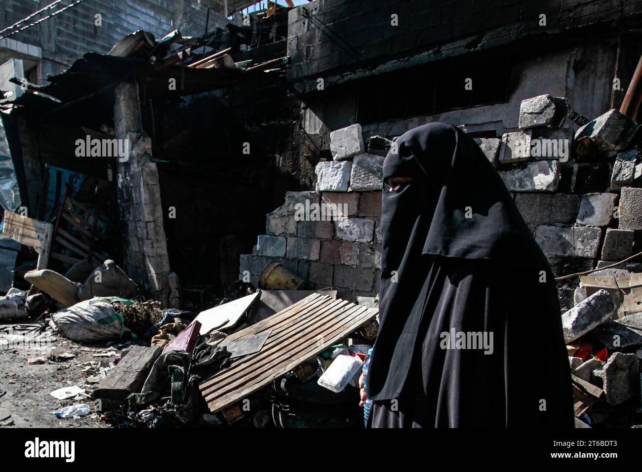 A Palestinian woman seen walks near a bombed building through a ...