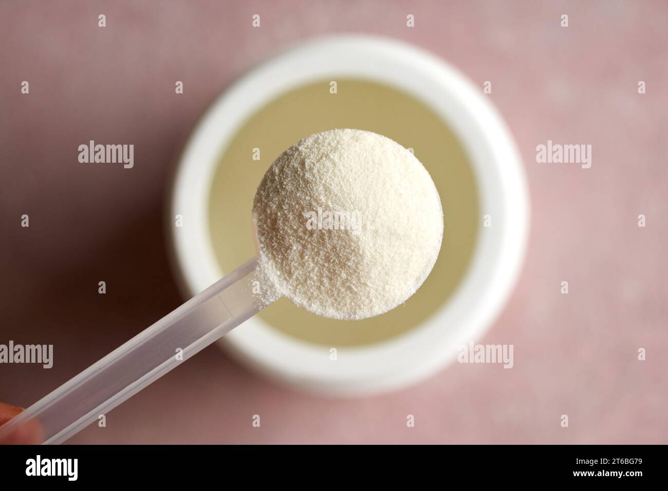 Collagen powder in a plastic measuring scoop above a plastic jar, top ...