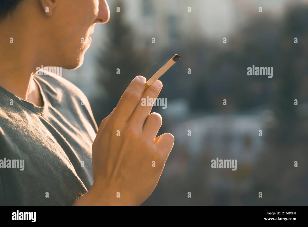 Young man is smoking cigarette near the window Stock Photo - Alamy