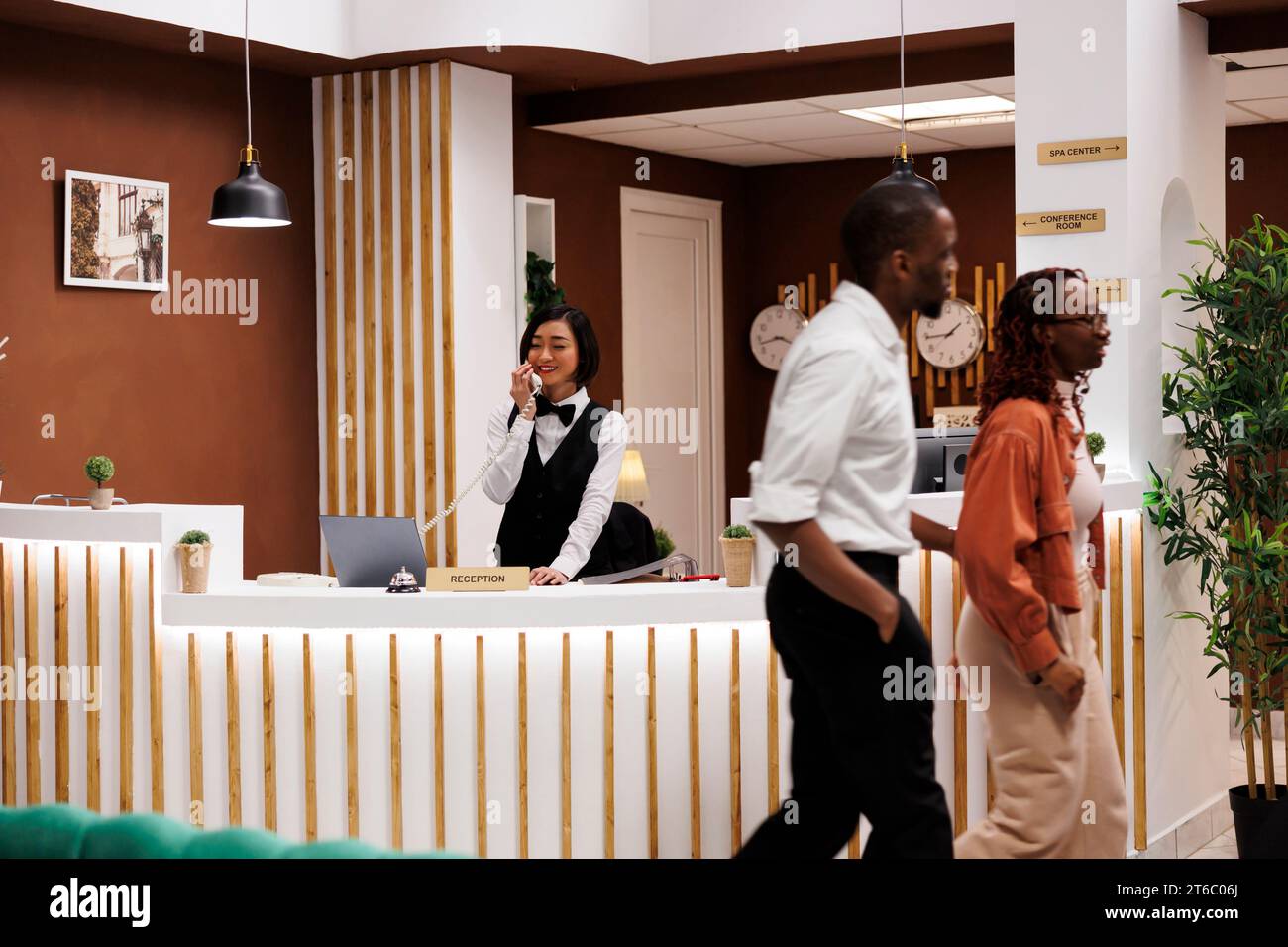 Asian receptionist making online booking using landline phone at ...