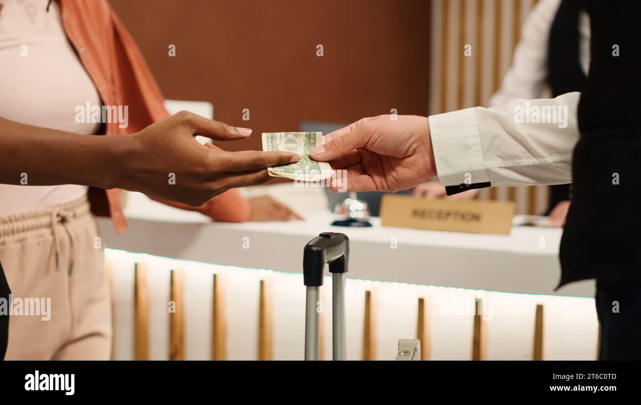 Close up of thankful hotel guest tipping helpful bellboy after ...
