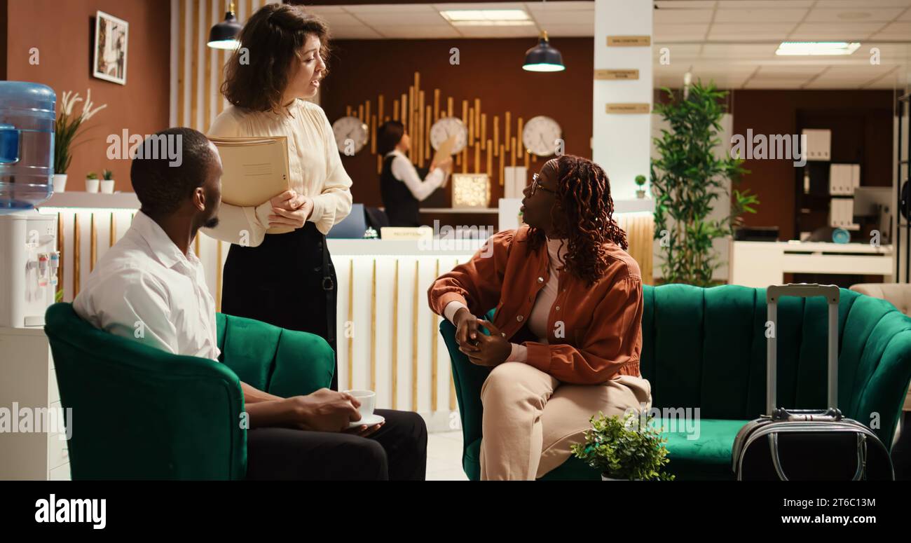 Friendly smiling hotel administrator taking tourist couple feedback ...