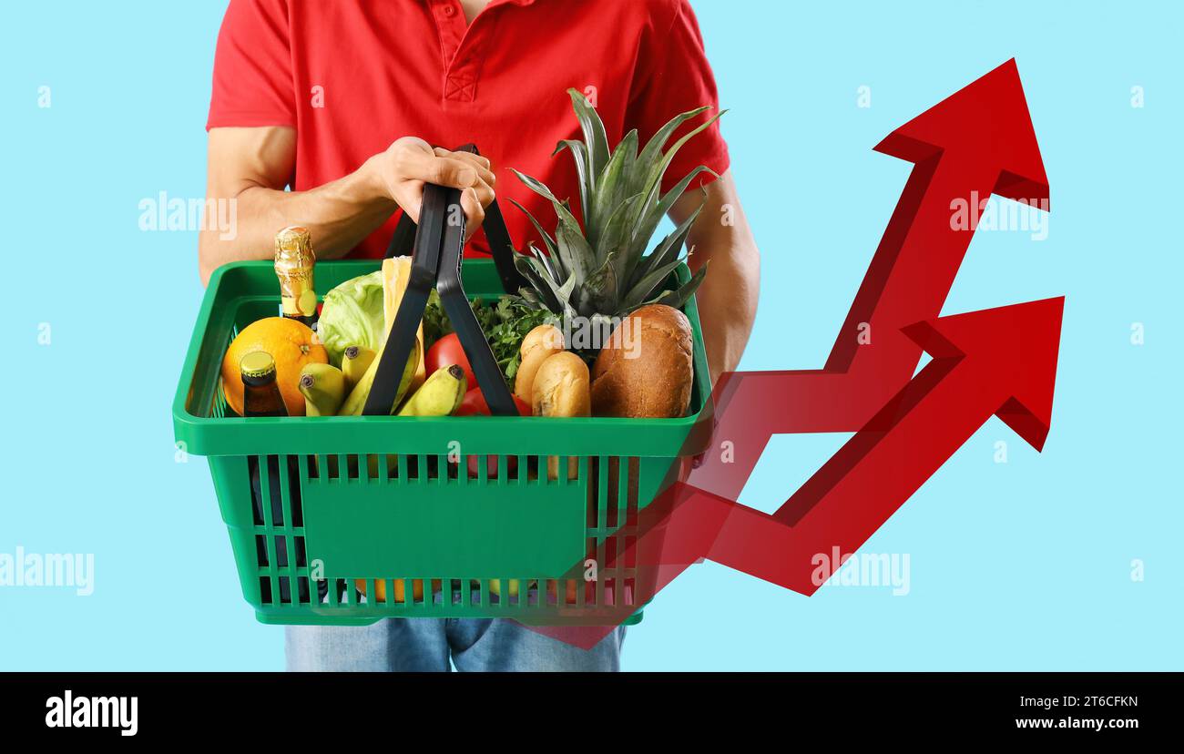 Man holding shopping basket with products on light blue background ...