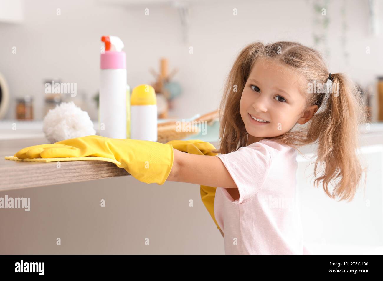 Cute little girl cleaning table in kitchen Stock Photo - Alamy