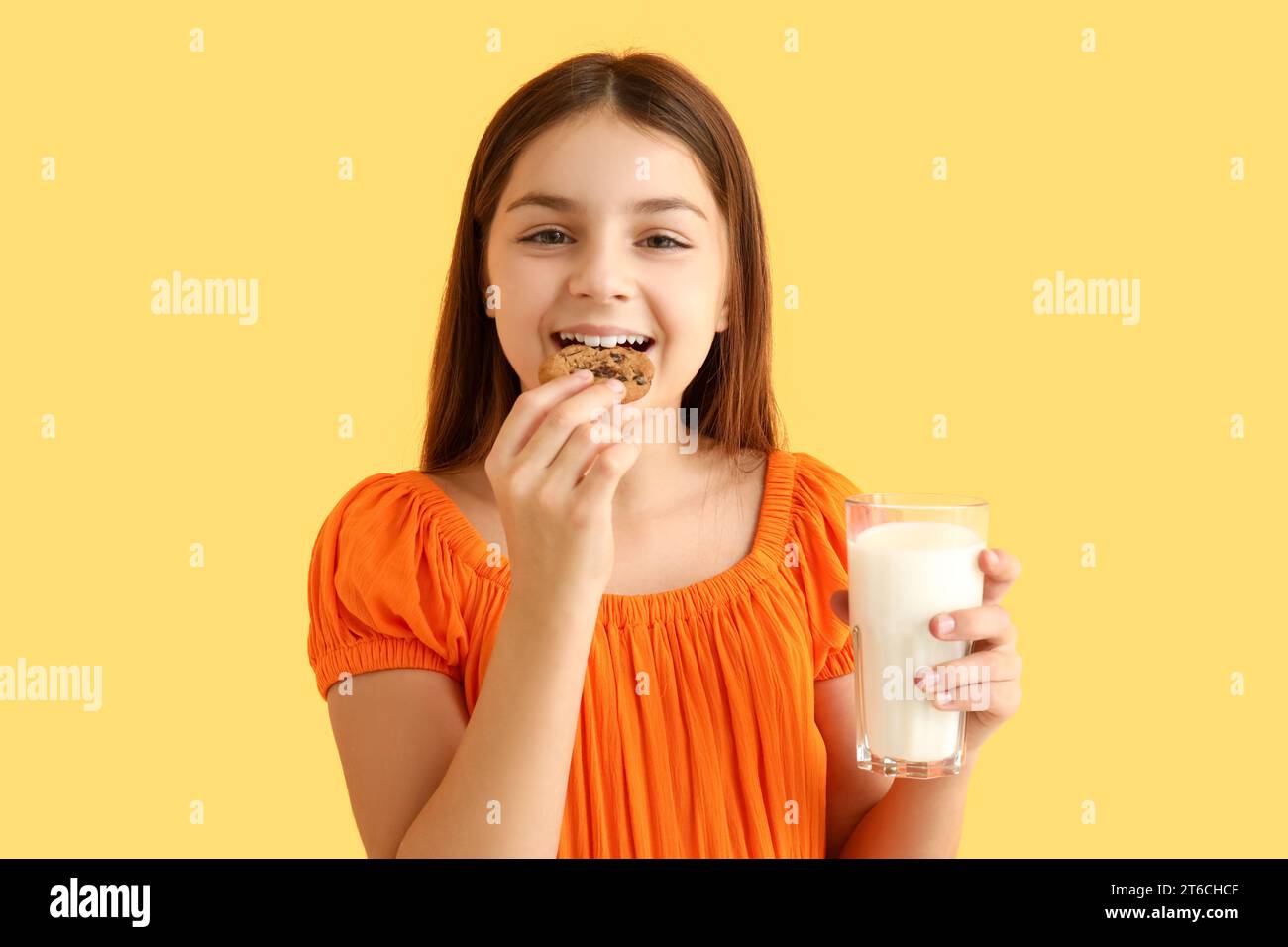 Little girl eating sweet chocolate cookie and drinking fresh milk on ...
