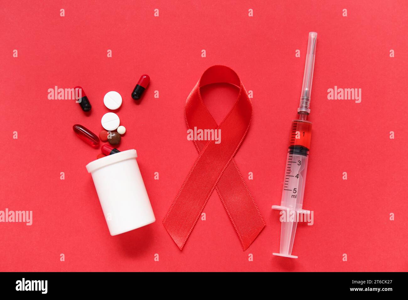 Red ribbon with pill bottle and syringe on color background. AIDS Day ...
