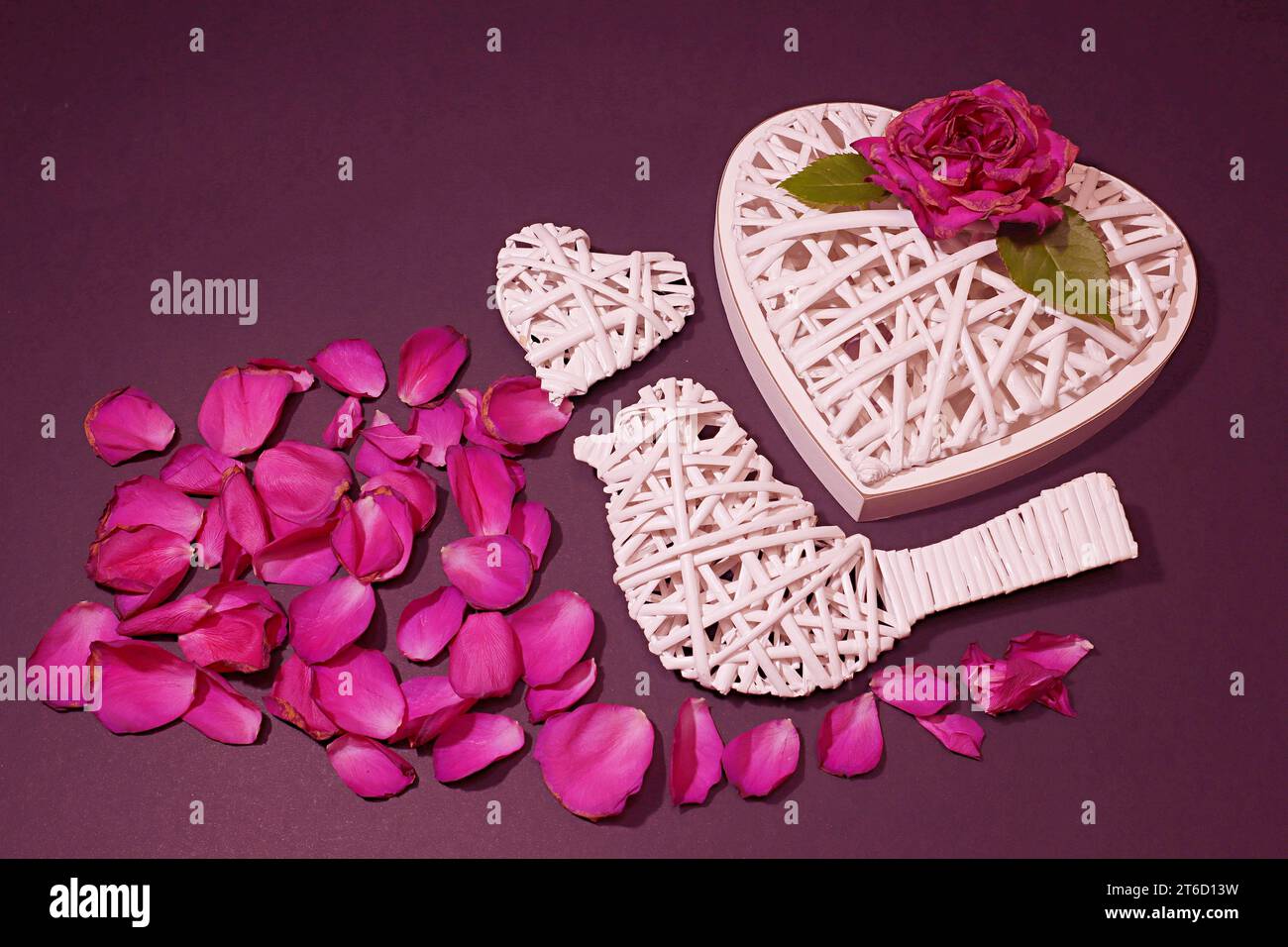 Wicker white bird, two hearts, blooming red rose and scattered rose petals Stock Photo - Alamy