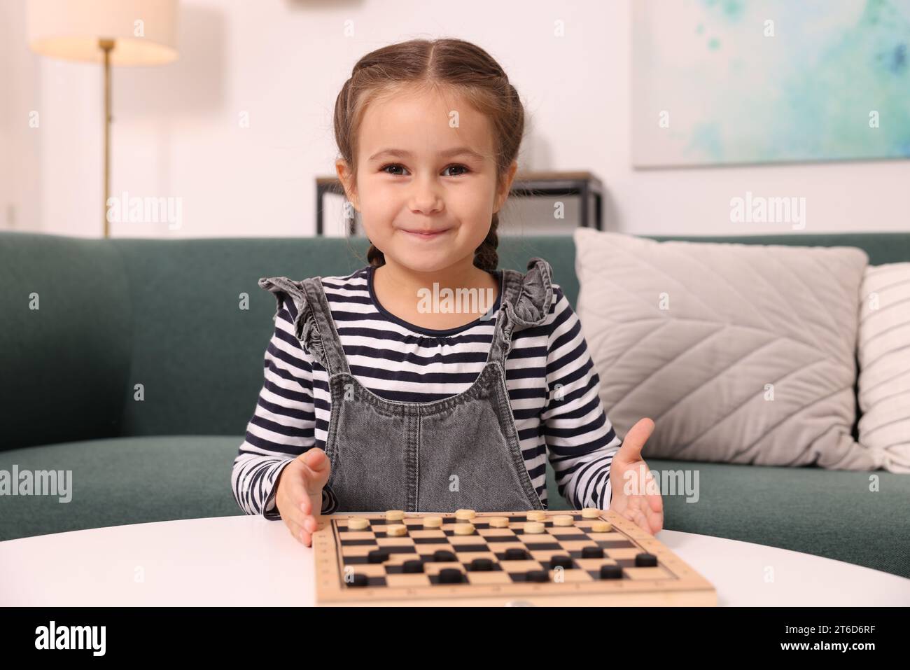 Cute girl playing checkers on sofa at home Stock Photo - Alamy