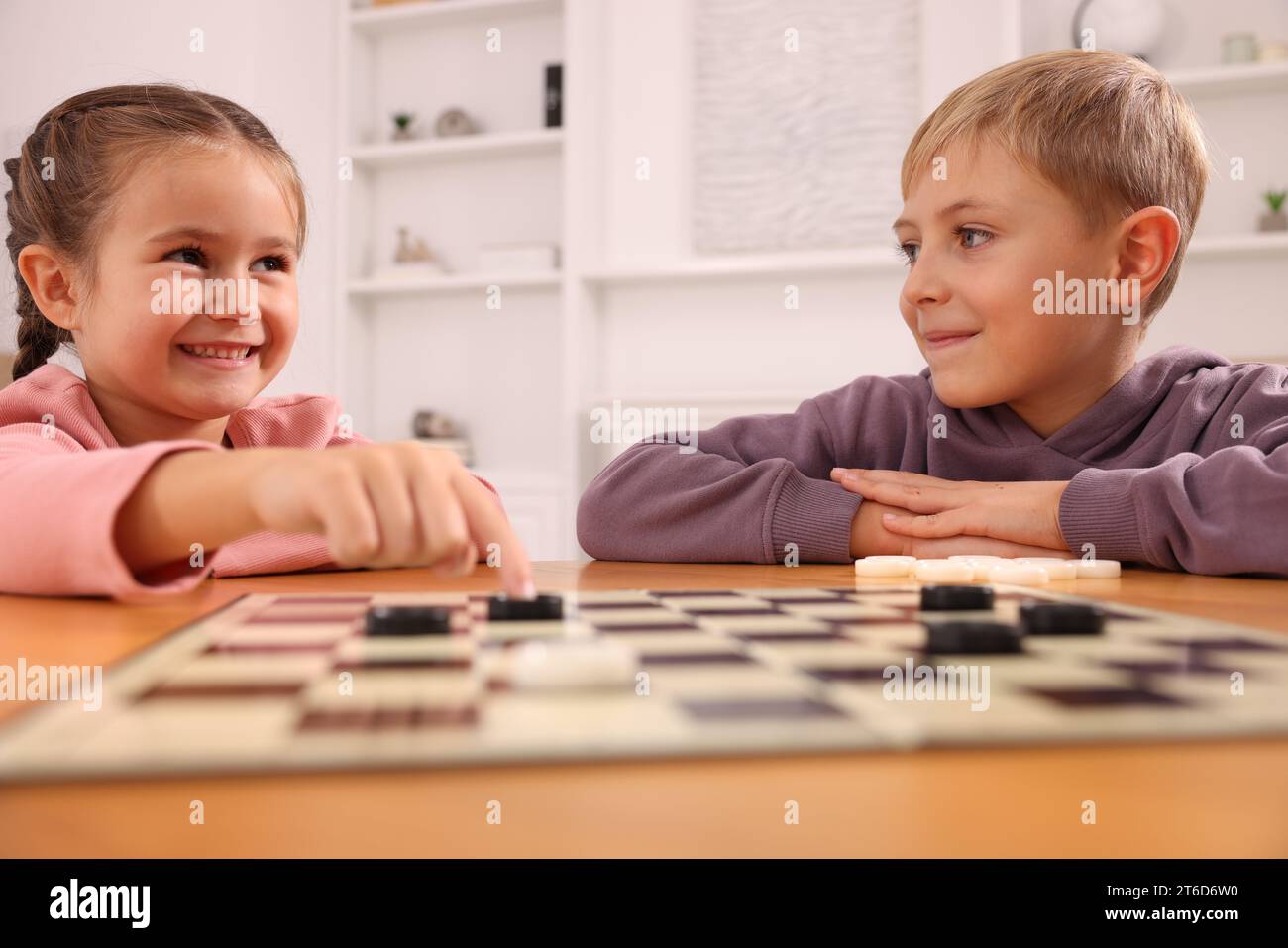 Children playing checkers at table in room Stock Photo - Alamy