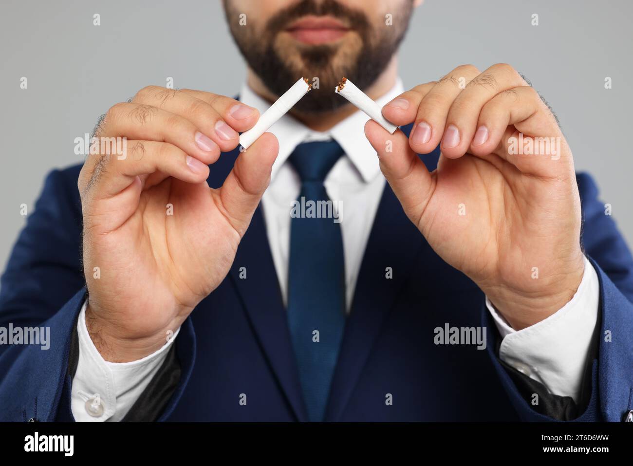 Stop smoking concept. Man breaking cigarette on light grey background ...