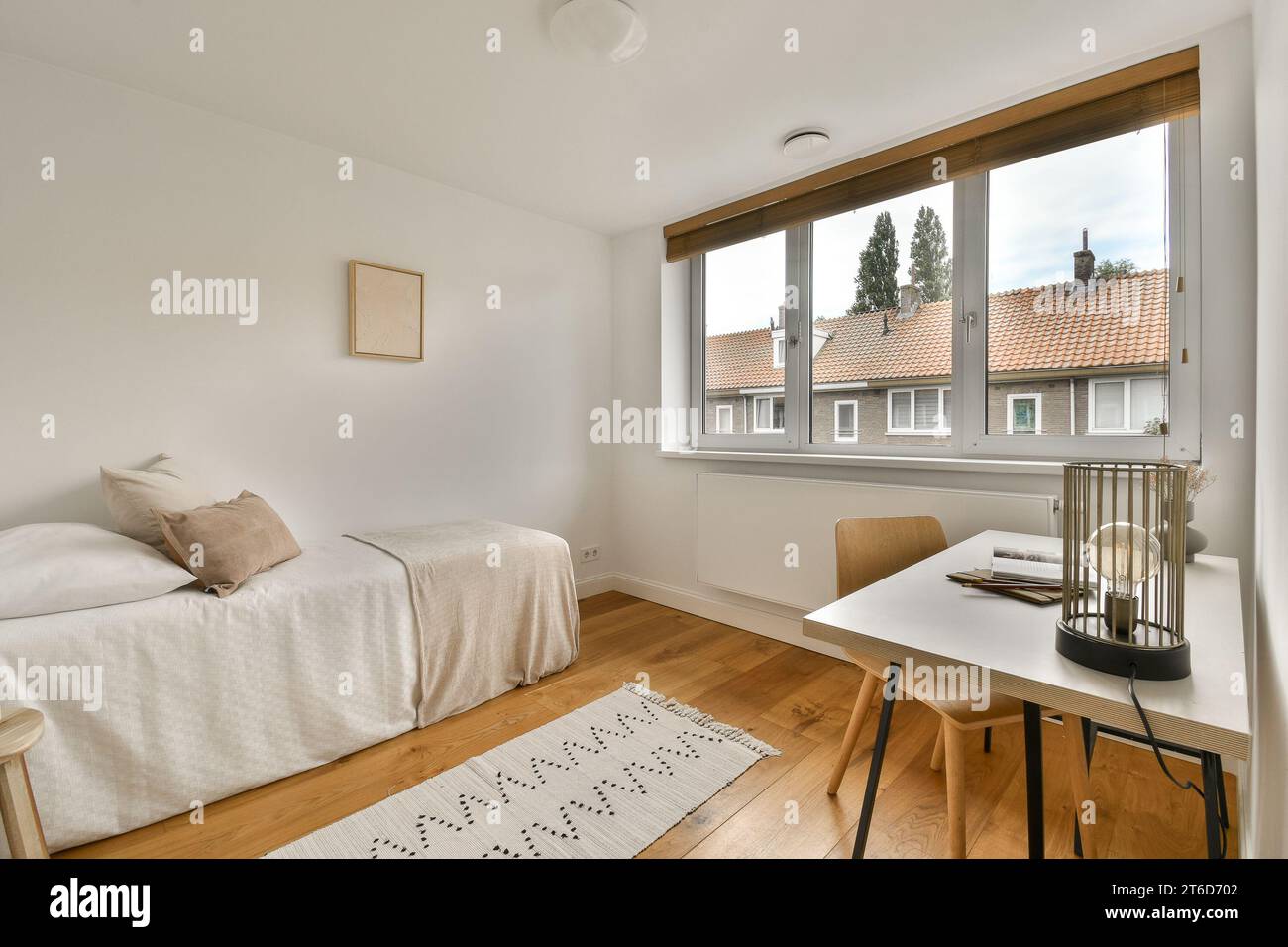 a bedroom with a bed, desk and window looking out onto the street in ...