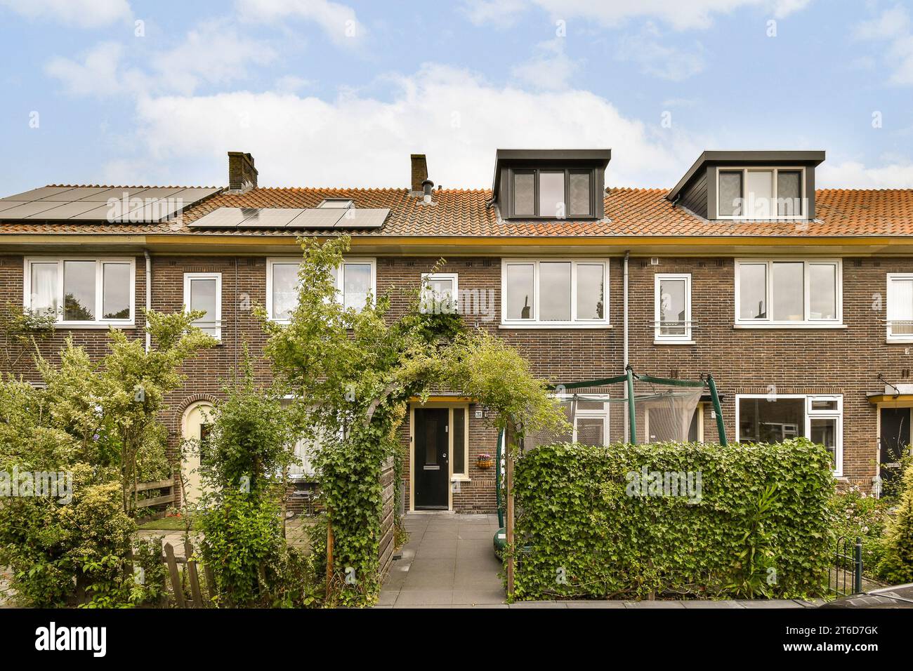 a row of houses with trees and bushes in the front yard, on a sunny day ...