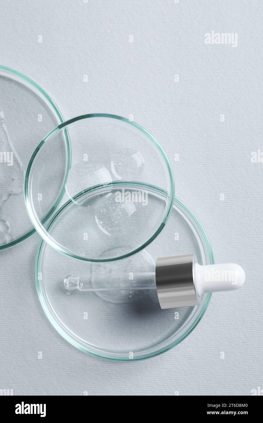 Petri dishes with samples of cosmetic oil and pipette on white ...