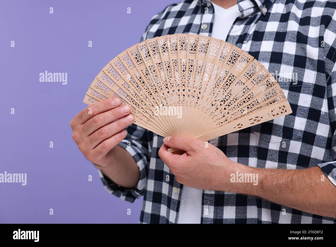 Man holding hand fan on purple background, closeup Stock Photo - Alamy