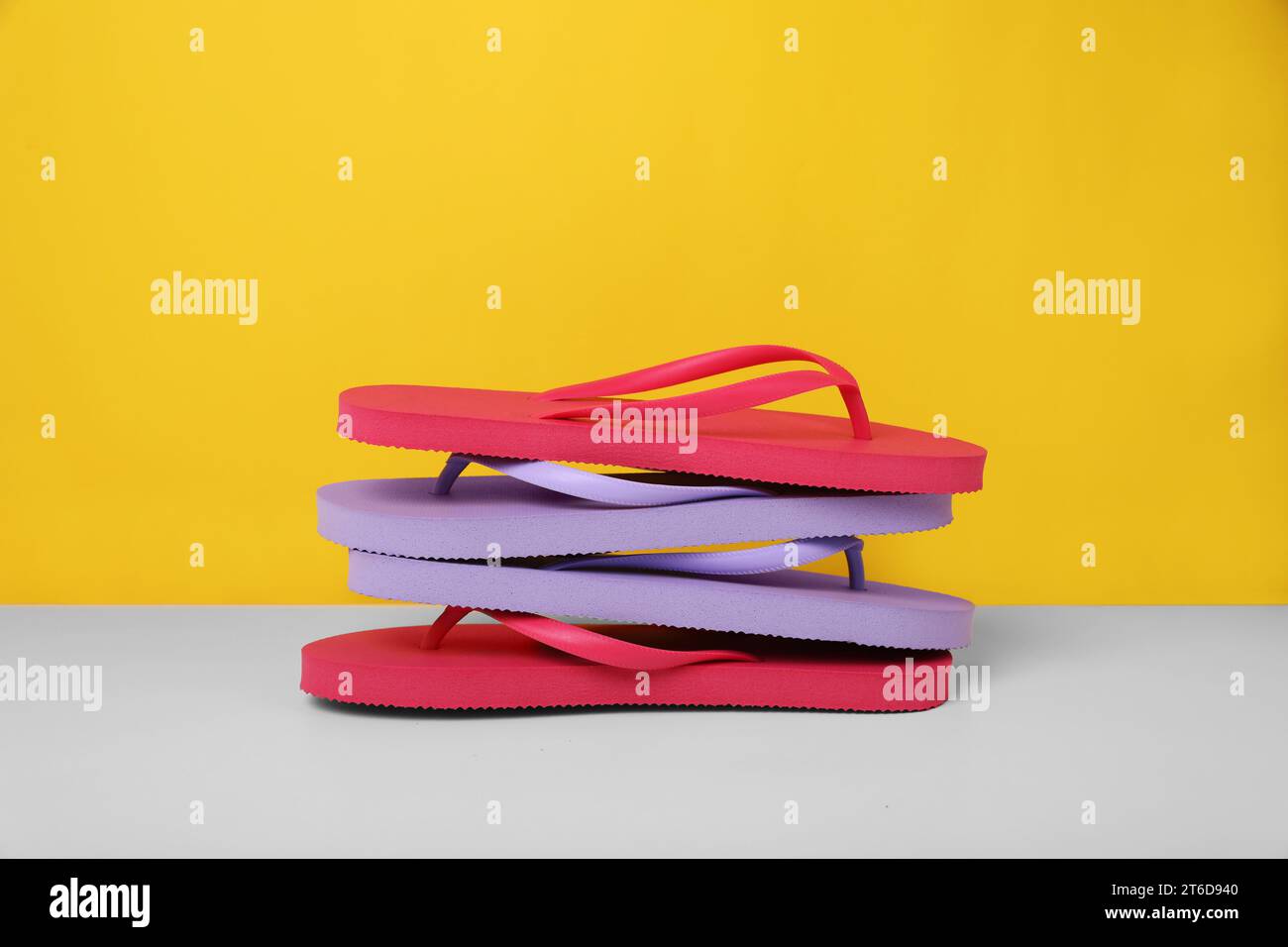 Stack of flip flops on white table against yellow background Stock ...