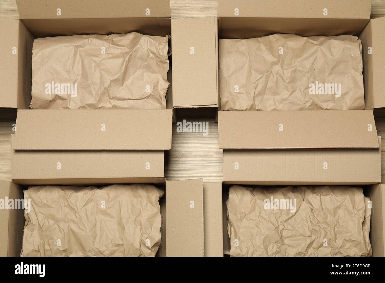 Many open cardboard boxes with crumpled paper on wooden floor, flat lay ...