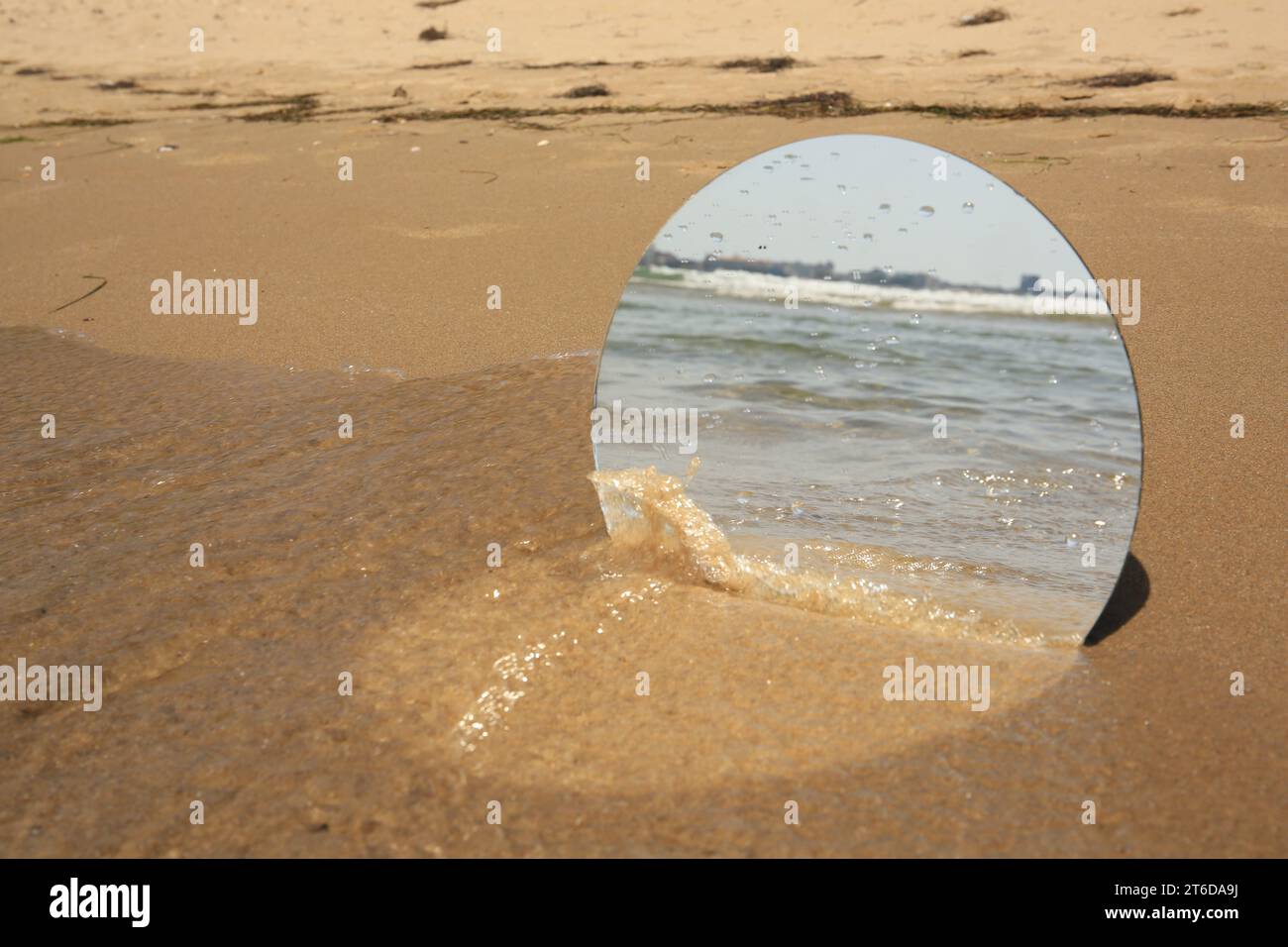 Round mirror reflecting sea on sandy beach Stock Photo - Alamy