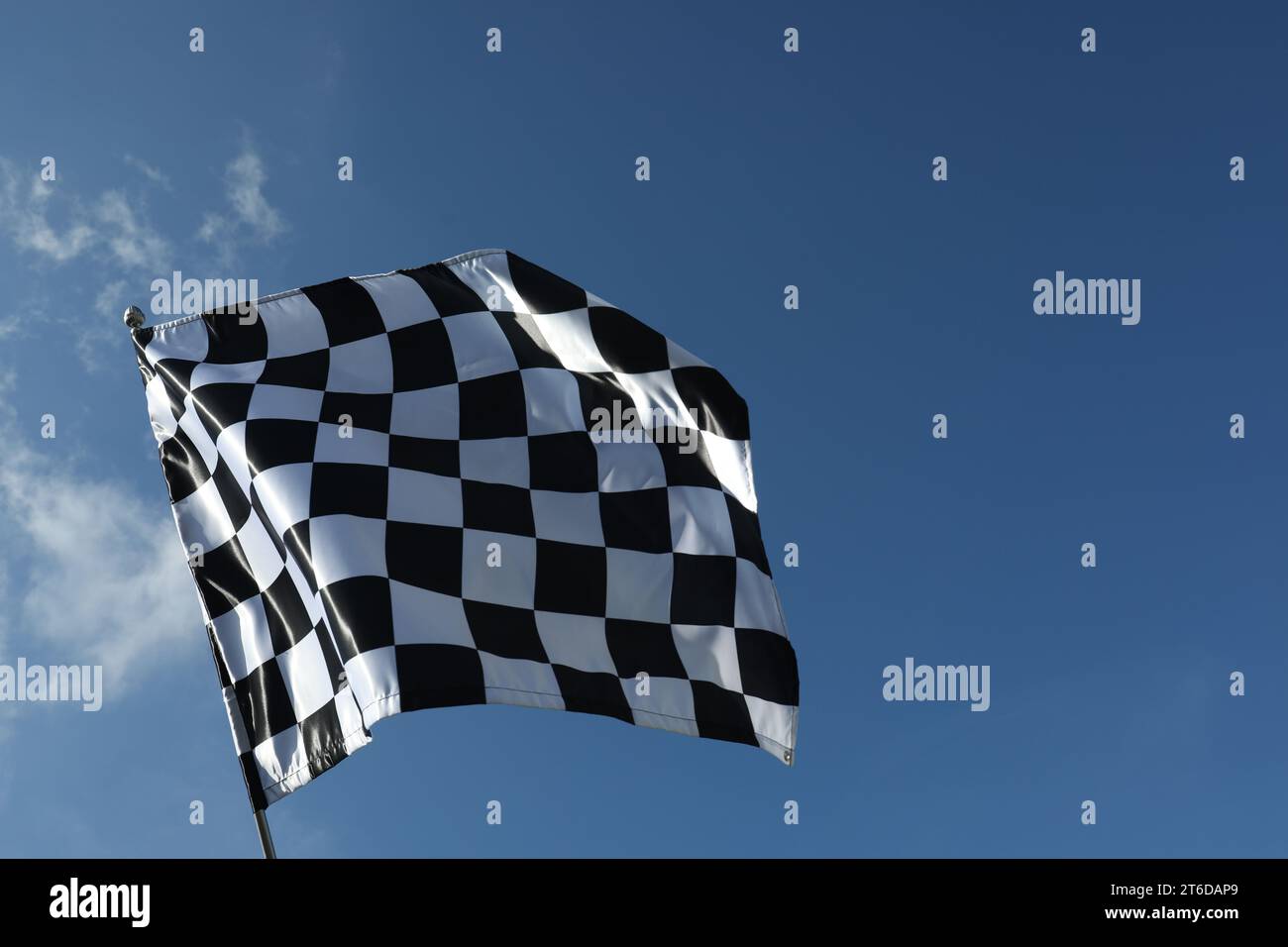 Checkered flag against blue sky outdoors, low angle view. Space for ...