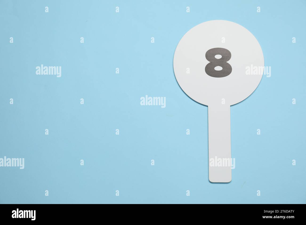 Auction paddle with number 8 on light blue background, top view. Space ...